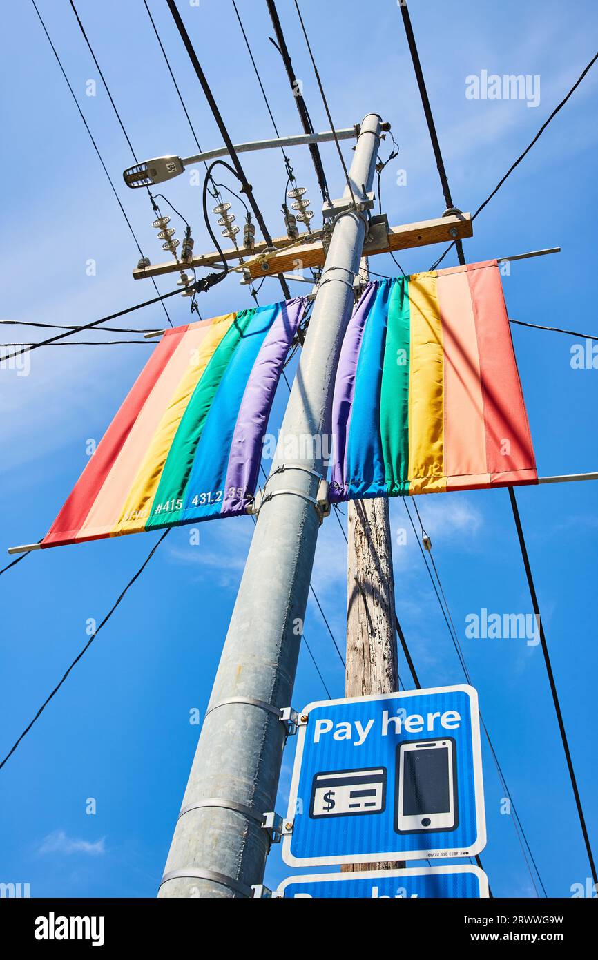 Upward view of two rainbow banners on street light pole with bright ...