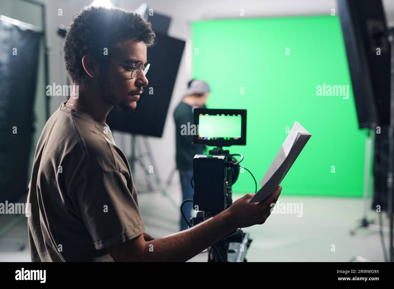 Young professional cameraman reading script before shooting in studio ...