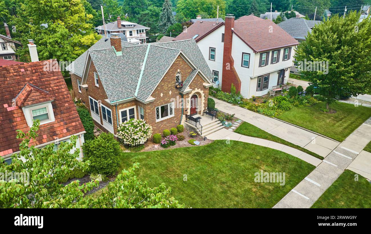 Low aerial of old brick building in neighborhood with landscaped lawns ...