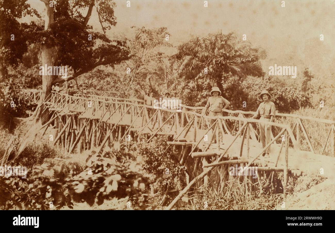 Two European men in pith helmets and several African men in small ...