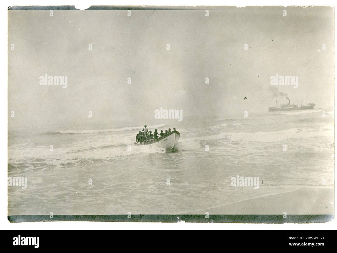 A group of African men steer a rowing boat in choppy waters off the ...