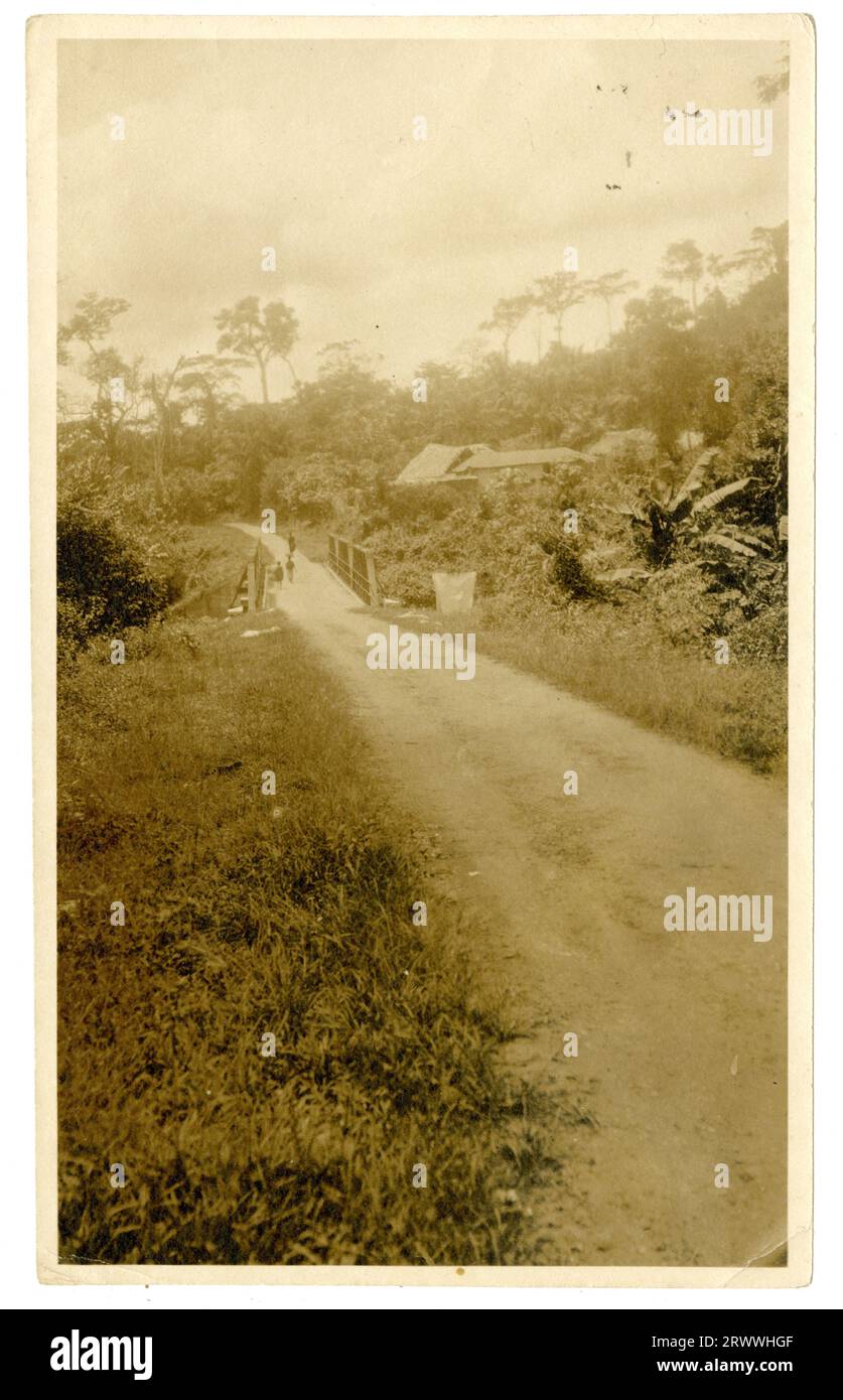 View down a quiet country road, with people walking across a bridge ...