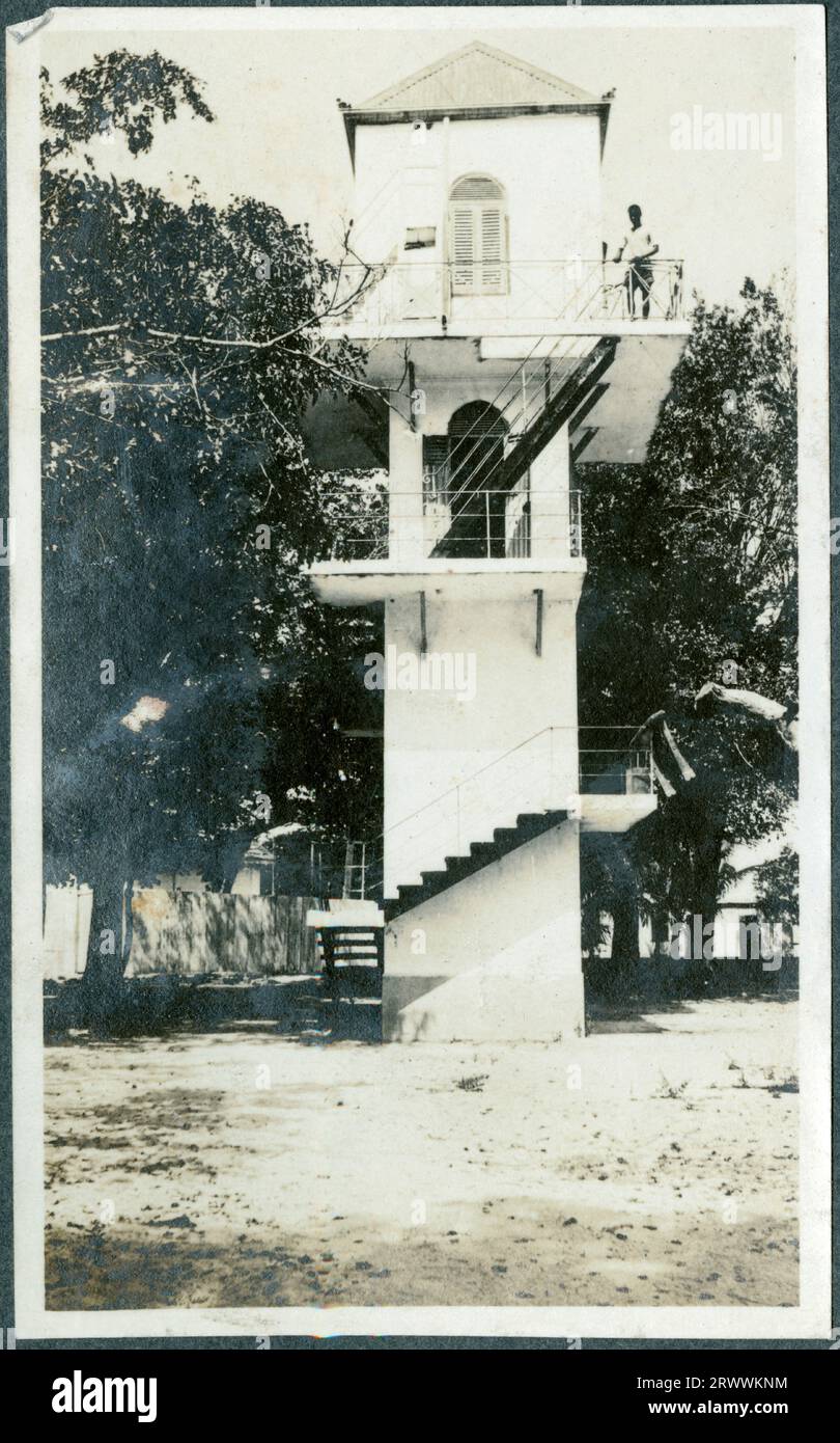 A tall observation tower stands in the shade of trees in an ...