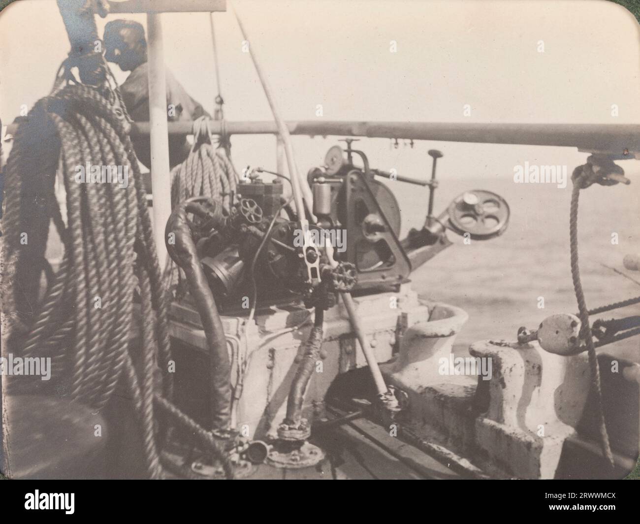 Close up of deep sea sounding engine on deck, with sailor in attendance ...