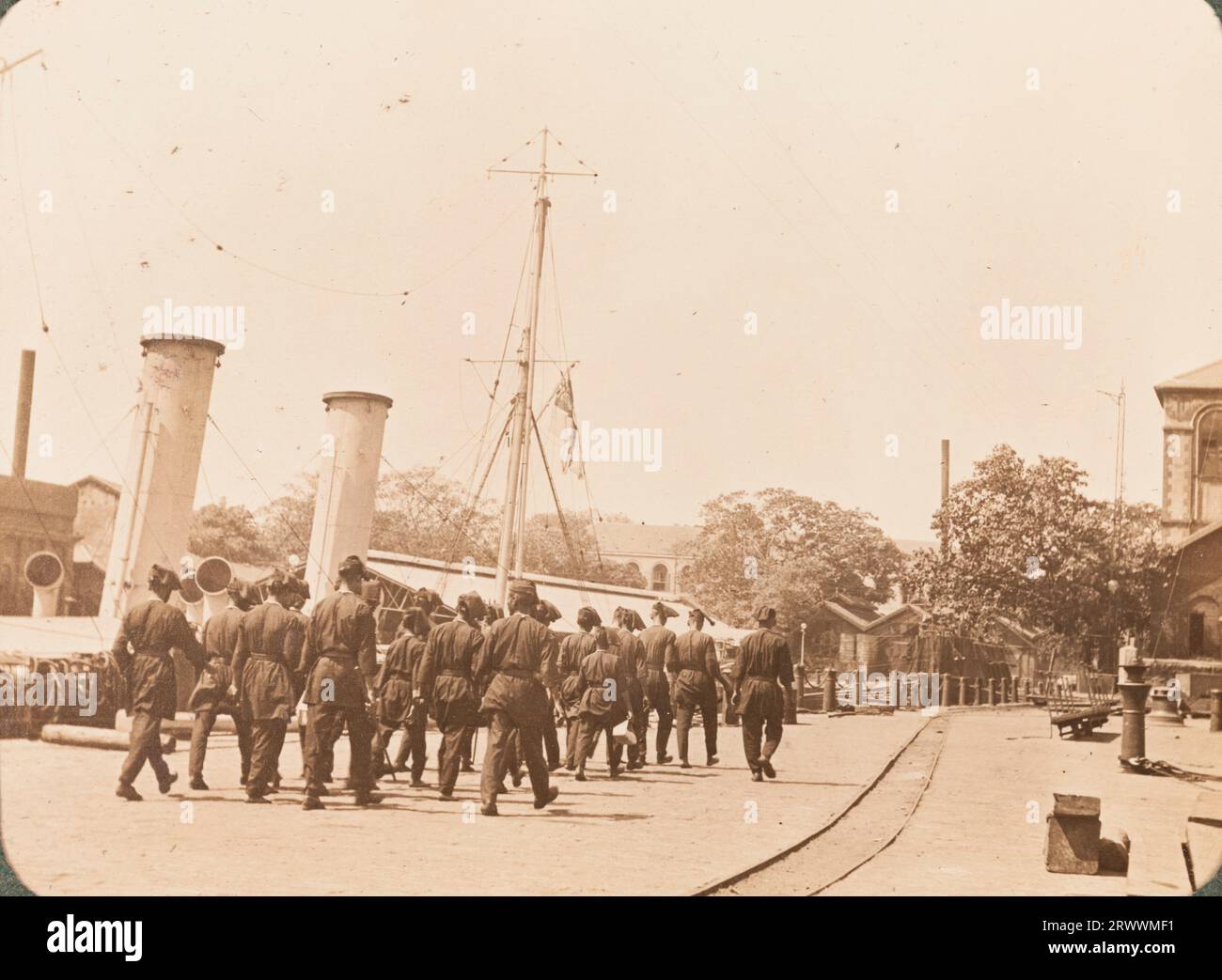 Group of uniformed crew march at ease along quayside close to twin ...
