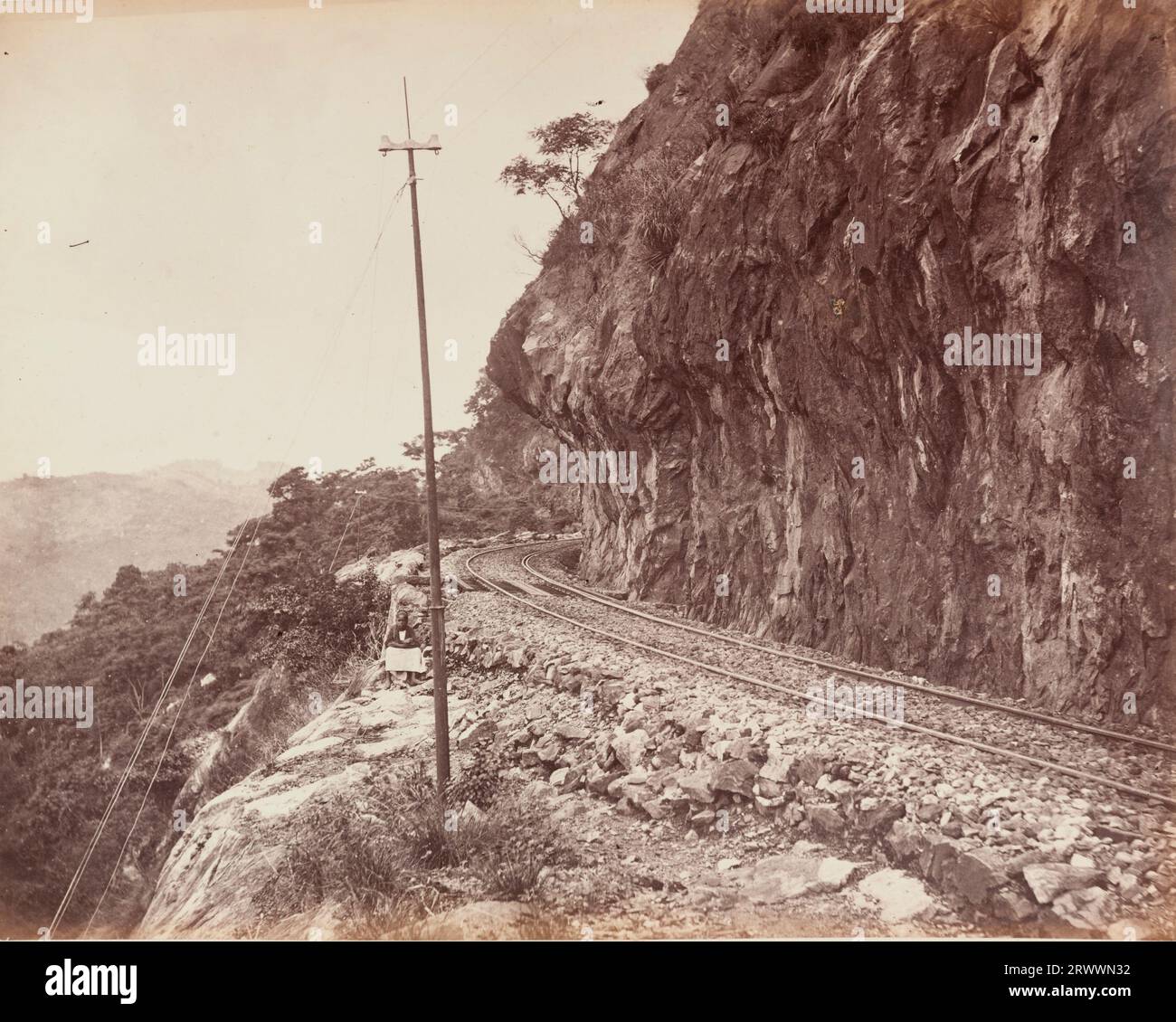 A section of railway track comes around a corner of a hillside with a ...