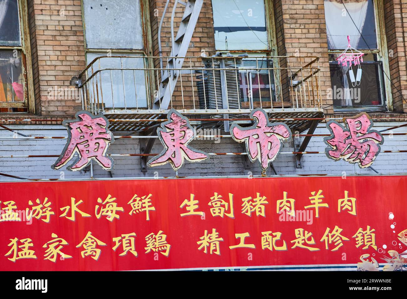 Chinese sign below worn down fire escape with red banner in Chinatown ...