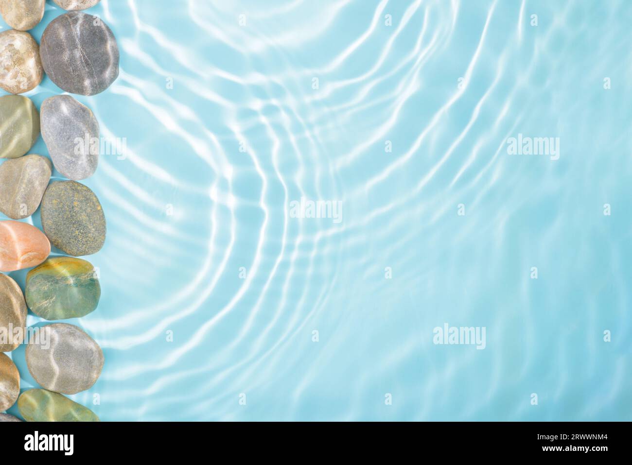 stones with sun lights shadow in ripple water over abstract blue ...