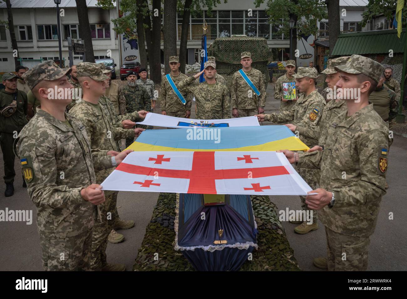 Ukrainian soldiers hold Georgian and Ukrainian flags during a funeral ...