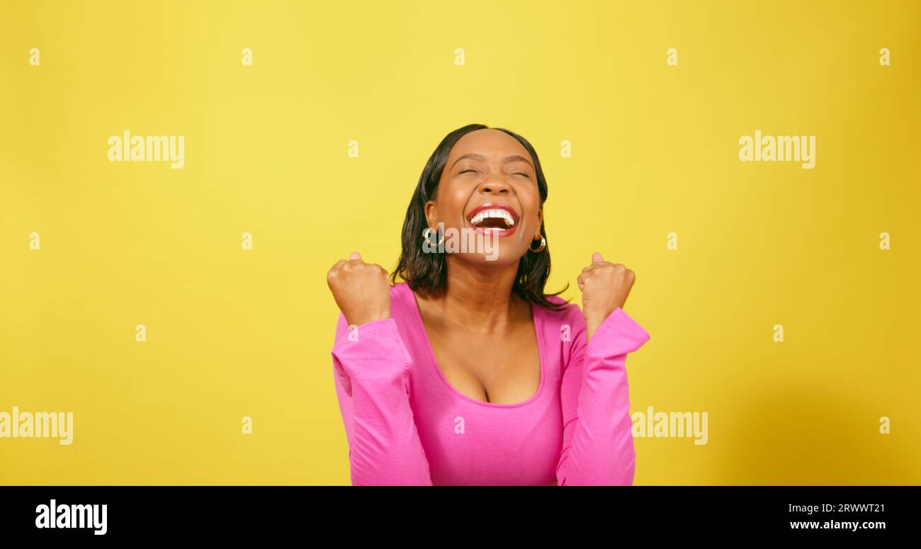 Excited woman cheers, winning happy dance, yellow studio background ...