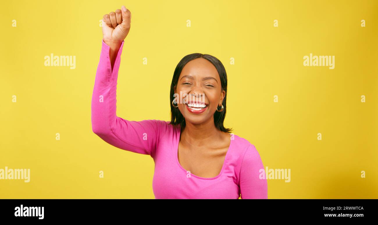 Young Black woman raises hands, yells excitedly, yellow background ...