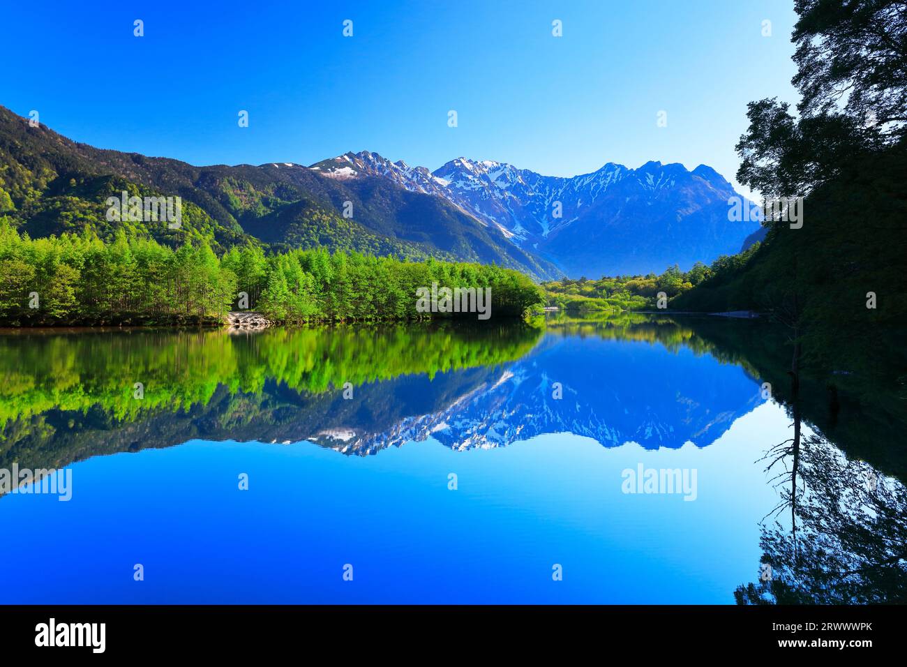 The Hotaka mountain range with lingering snow under clear sky from Taisho Pond, Kamikochi Stock ...