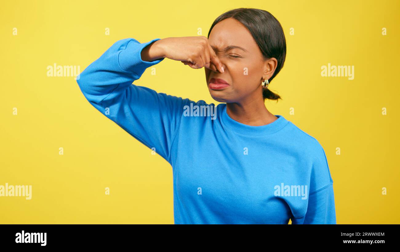 Beautiful young woman pinches nose smells bad odour stink, yellow ...