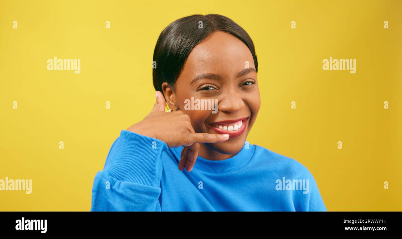 Cute young woman makes Call Me symbol with hand, flirting, yellow ...