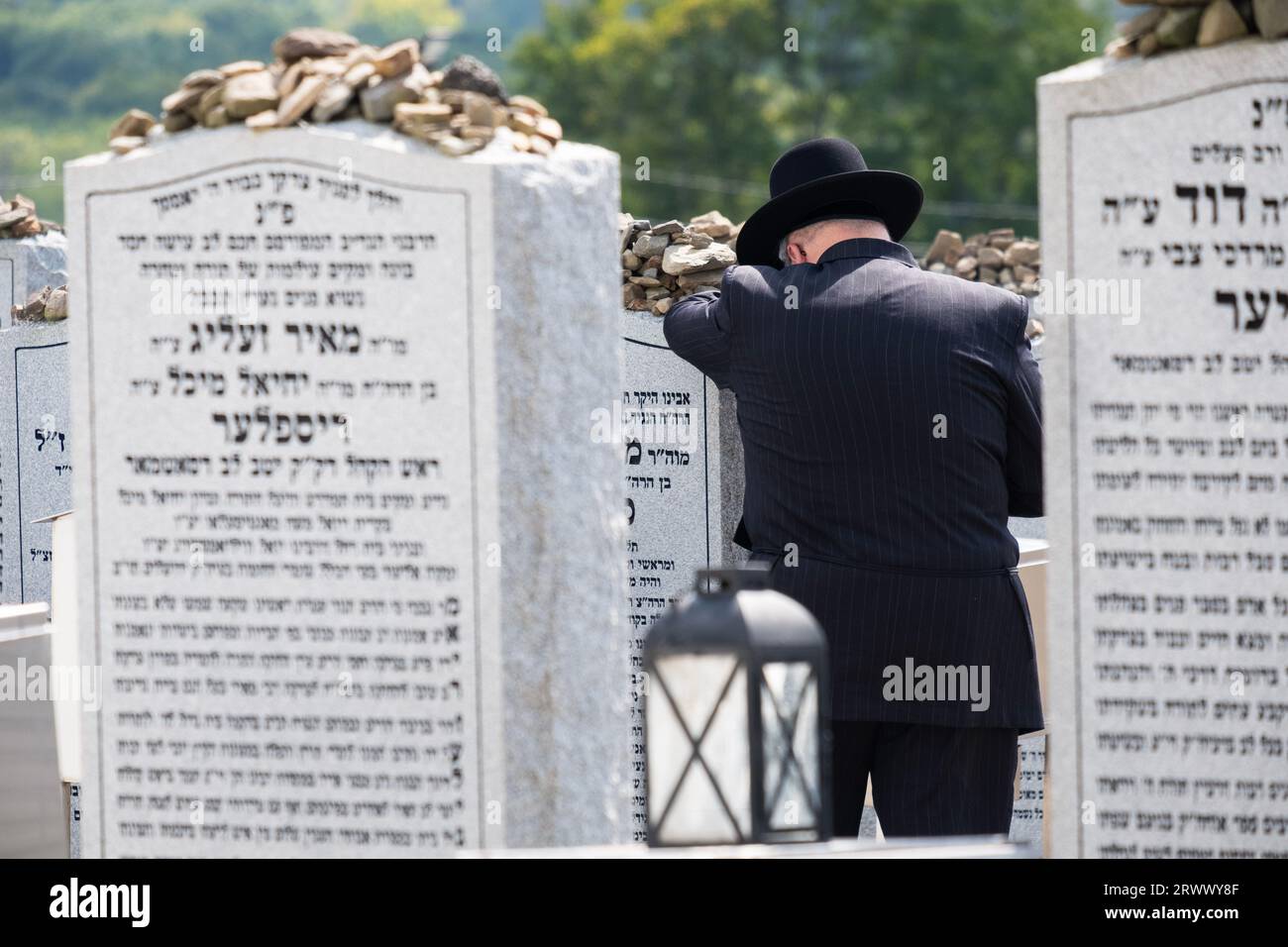 An anonymous orthodox Jewish man prays fervently at the headstone of a ...