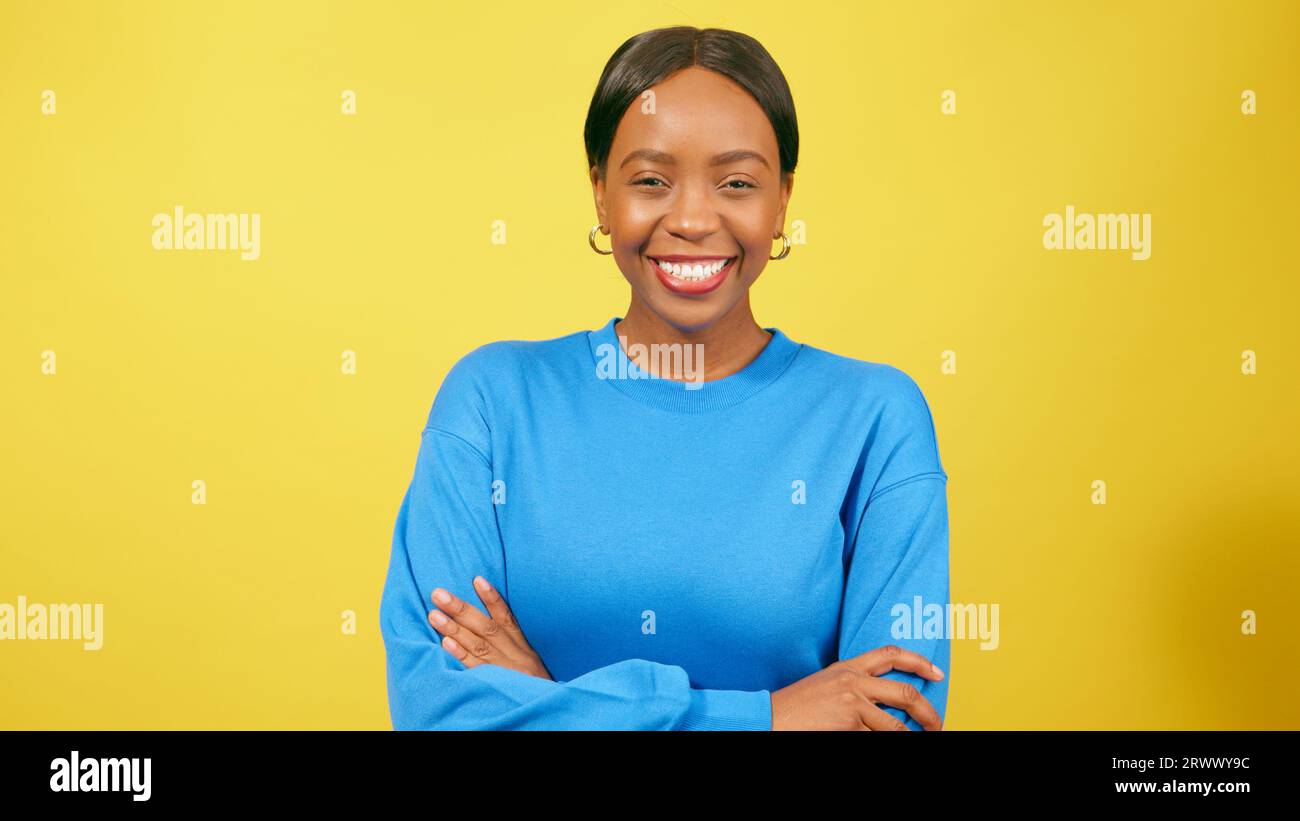 Laughing young woman folds arms, yellow background studio Stock Photo ...