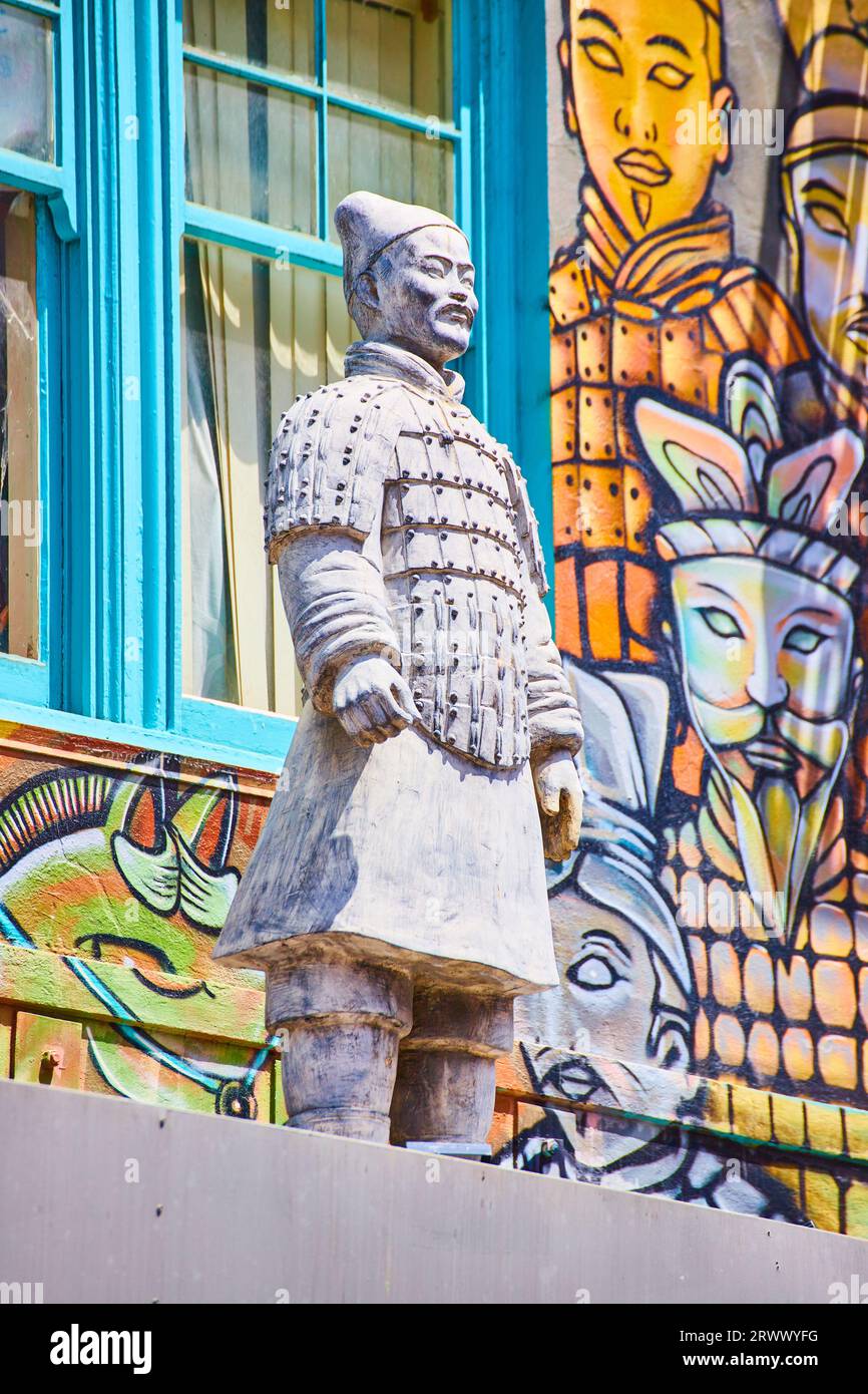 Chinese statue of man standing in front of soldier mural with bright ...