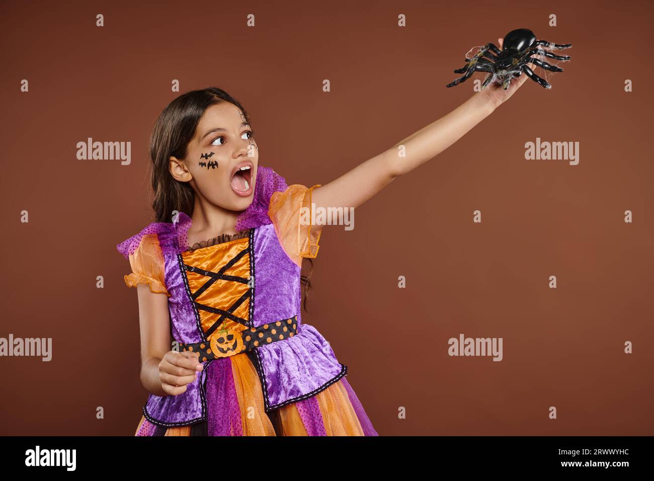 scared girl in Halloween costume looking at black spider and screaming ...