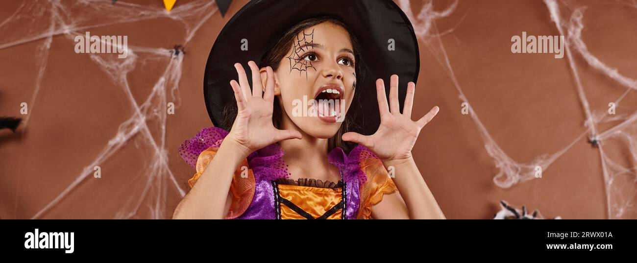 emotional girl in witch hat and Halloween costume screaming on brown ...