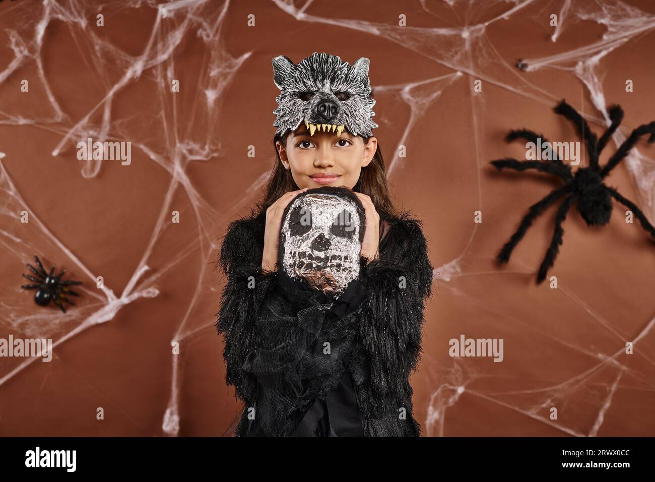 smiling girl in wolf mask and black attire hugging Halloween toy ...