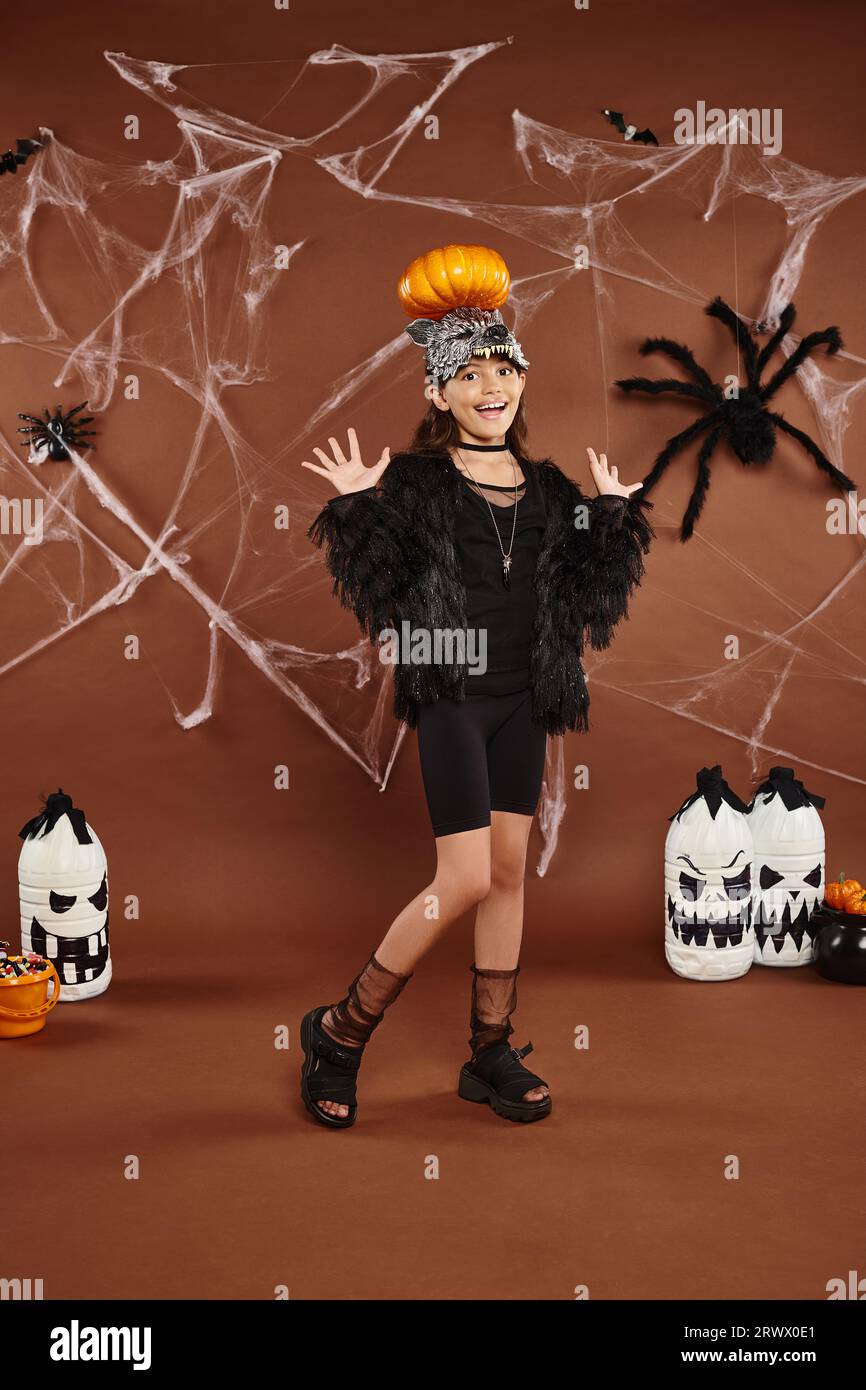 preteen girl holding pumpkin on her head with raised hands, brown ...
