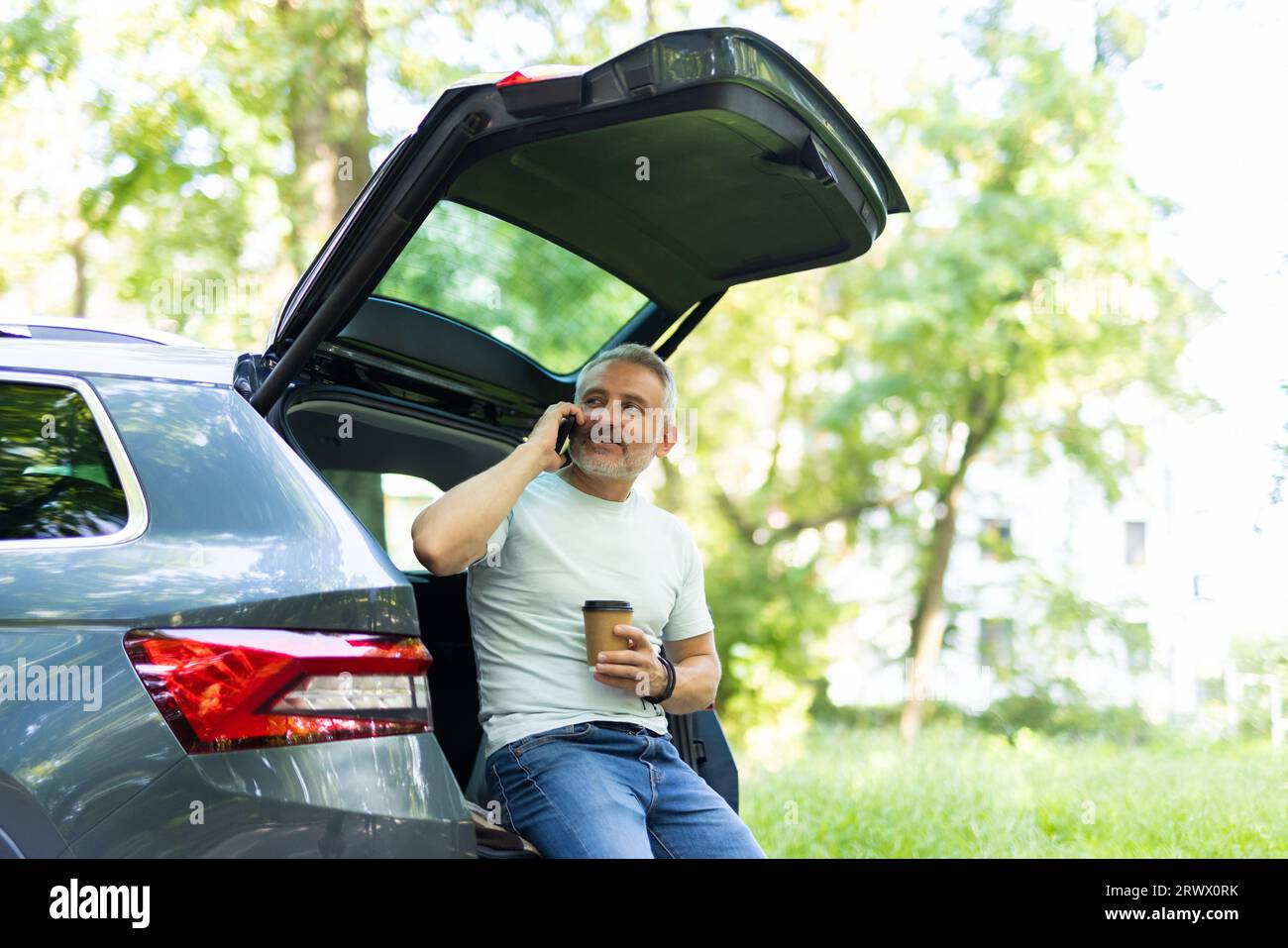 Young travel man sitting in car trunk talk on phone Stock Photo - Alamy