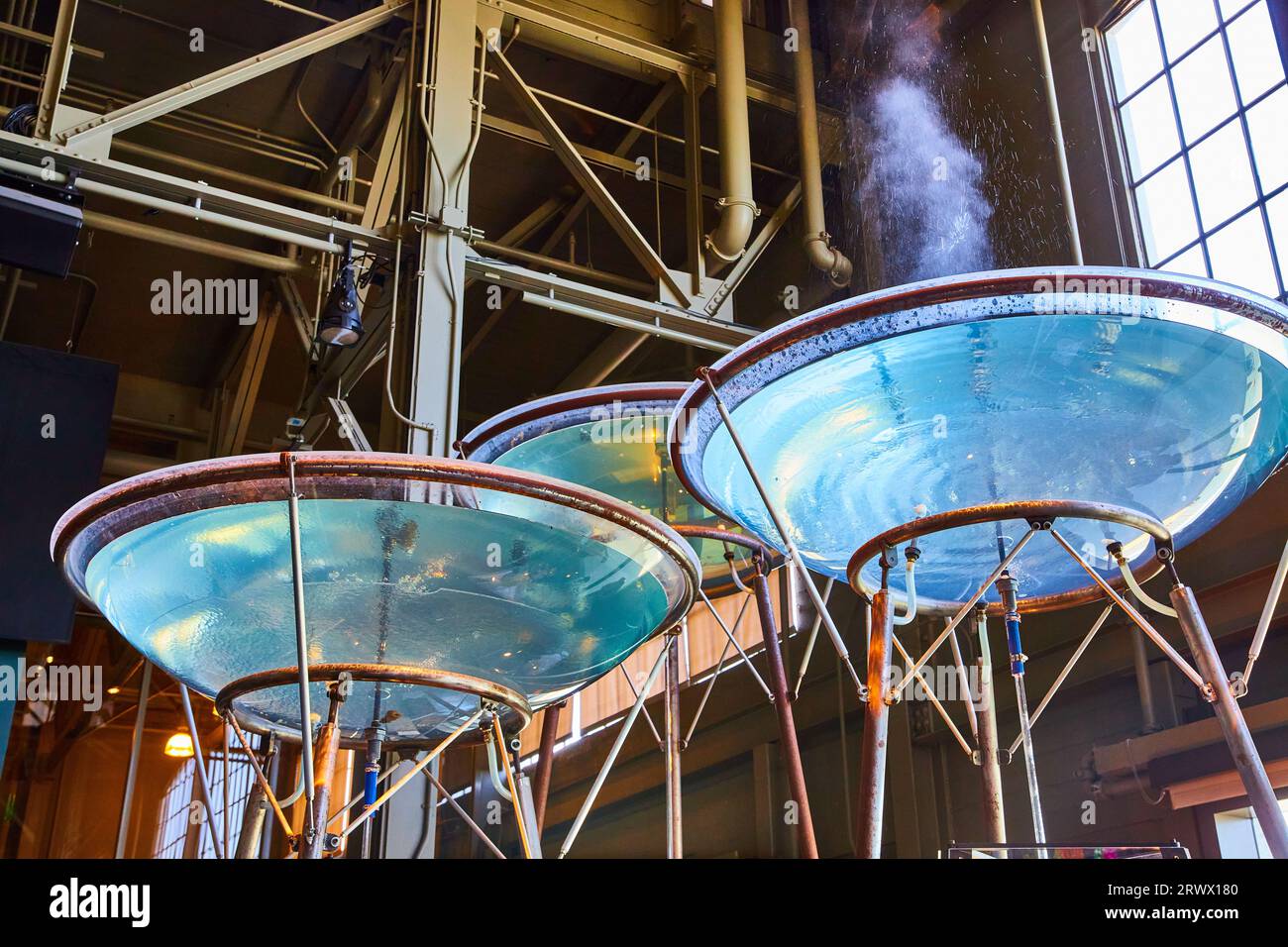 Giant vats of water in clear bowls on long copper stands with one ...