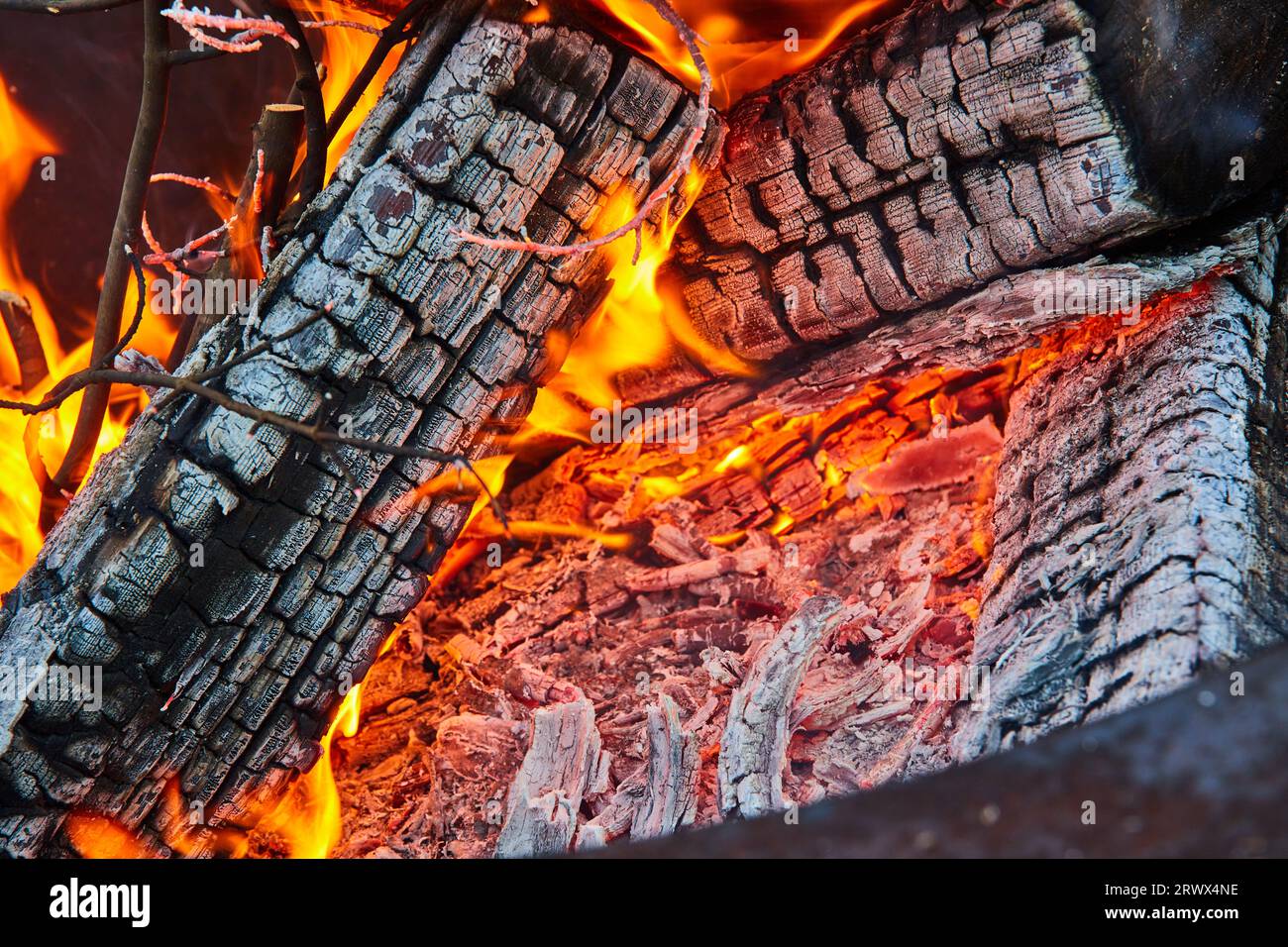 Ash covered logs with yellow and orange flames close up background ...
