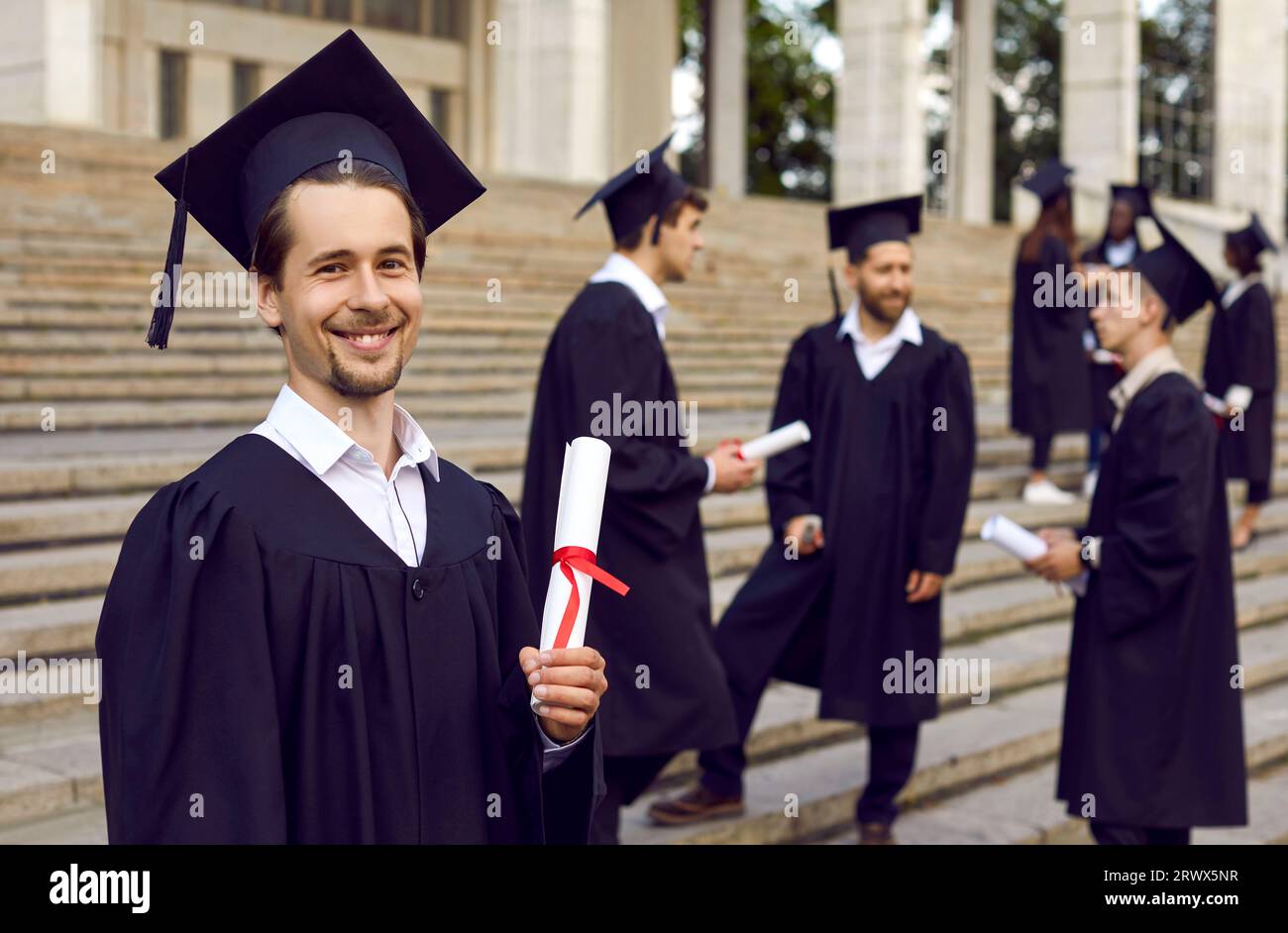 Young smiling confident man student in a university graduate gown and ...