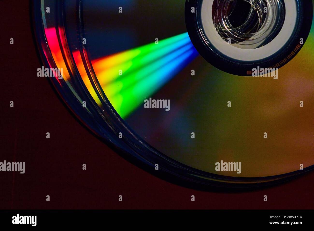 Stacked CDs in dark setting with cone of rainbow colored light shaft ...