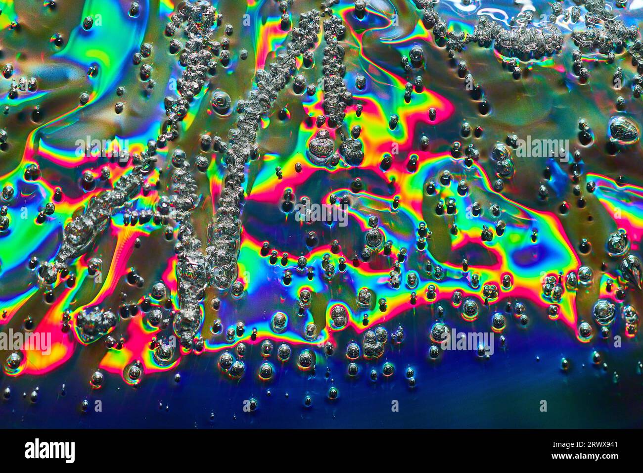 Rainbow colors in oil with silvery frothing bubble surface in abstract ...