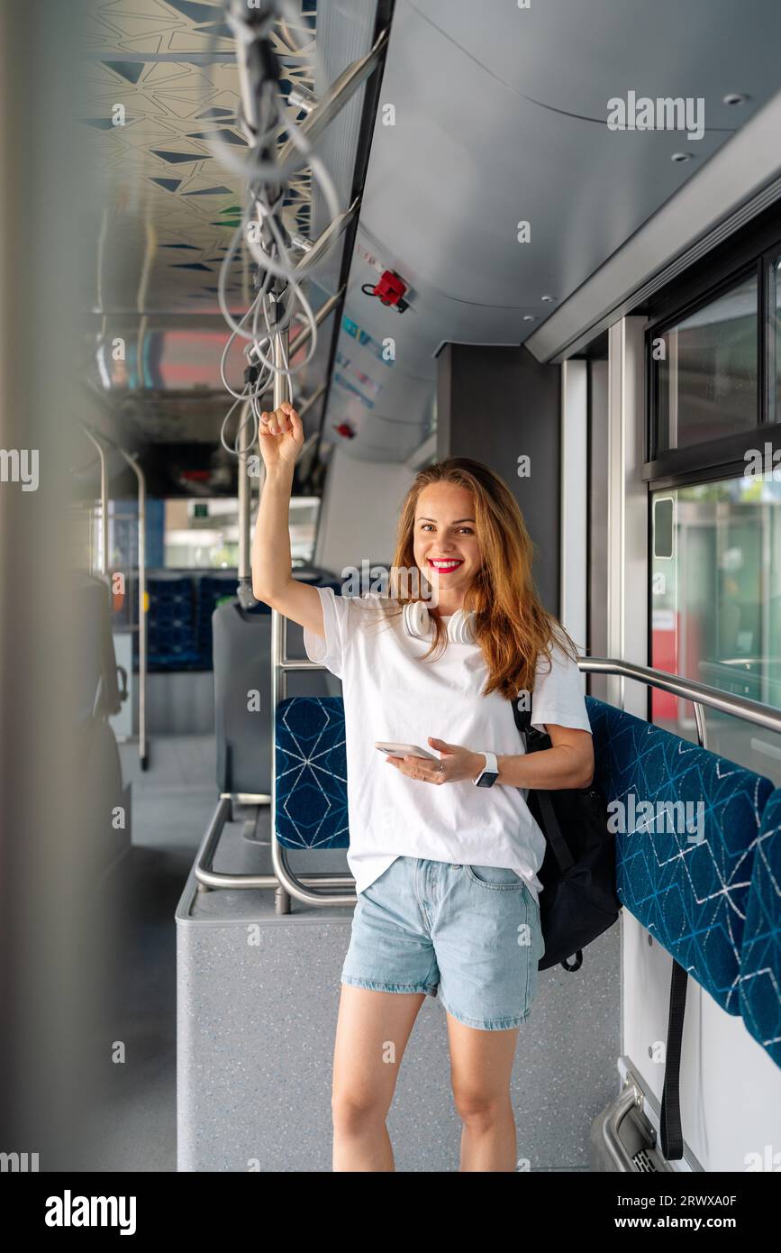 Attractive young adult urban brunette woman stands inside of trolley ...