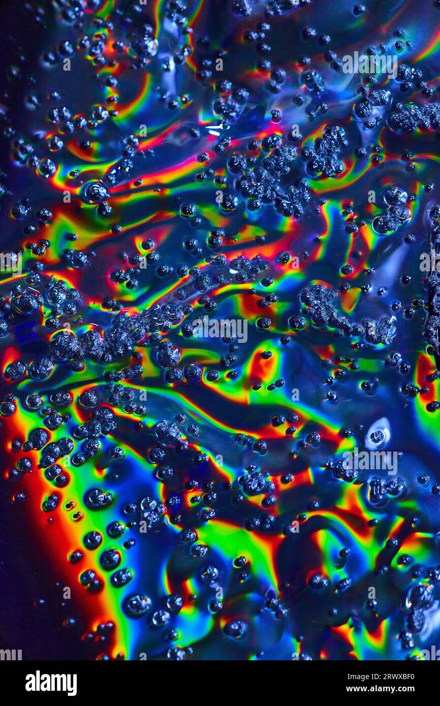 Abstract art of watery goo with bubbles foaming across colorful oily ...