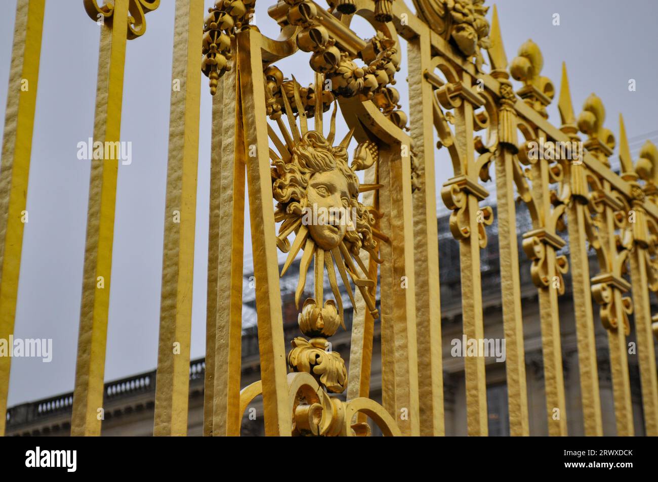 A side angle detail of the Sun King symbol on an ornate golden gate ...
