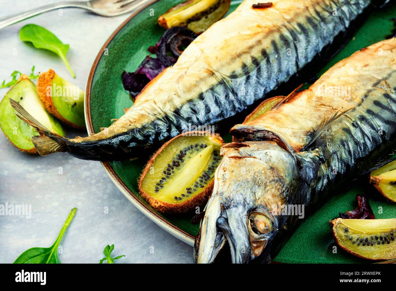 Whole tasty mackerel fish grilled with kiwi fruits Stock Photo - Alamy