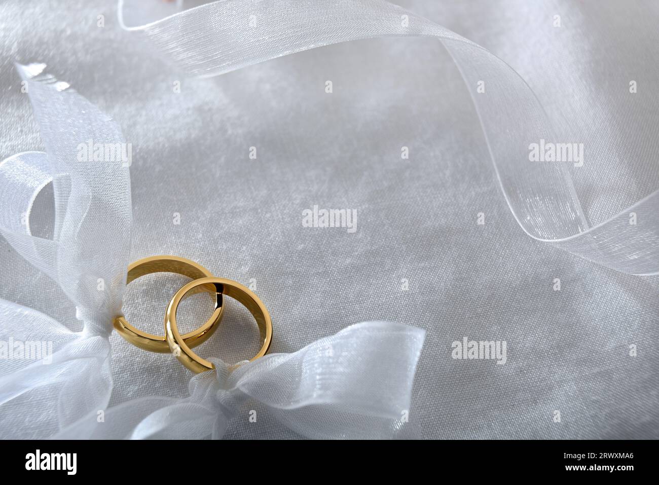 Two gold rings tied with ribbon on white cloth. Top view Stock Photo ...