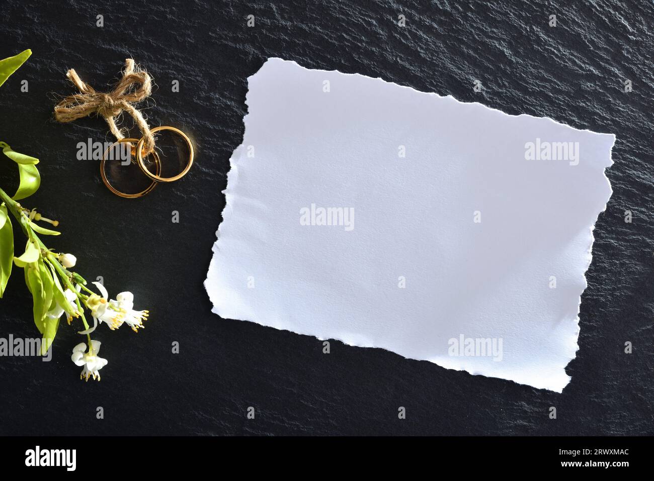 Paper white card on black slate background with rings bound with jute ...