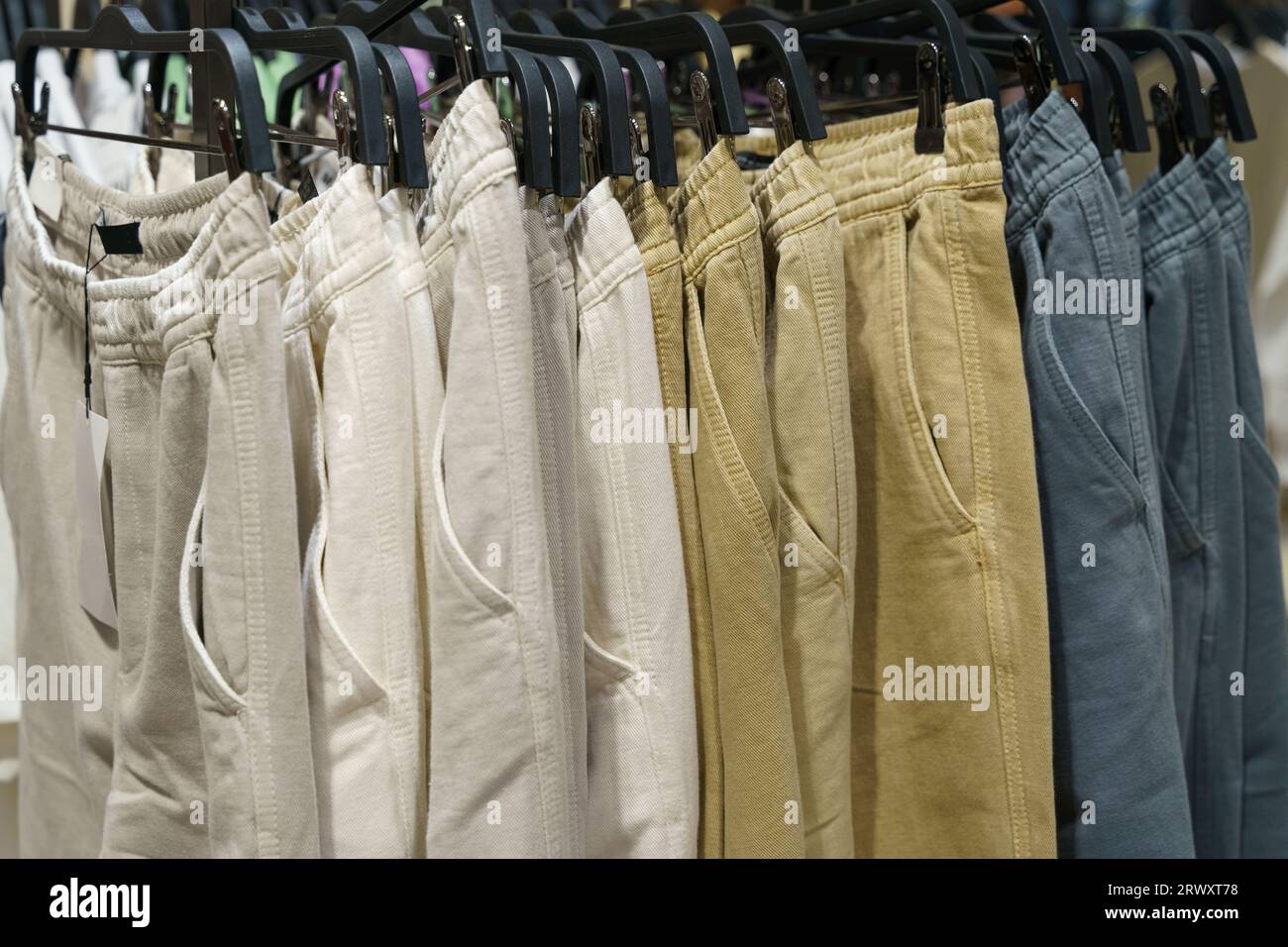 Men's trousers hang on hangers in a clothing store. Close-up ...
