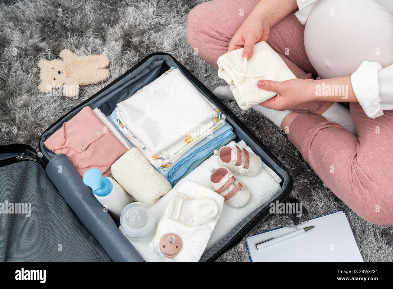 pregnant lady on the floor, deeply involved in packing her suitcase ...