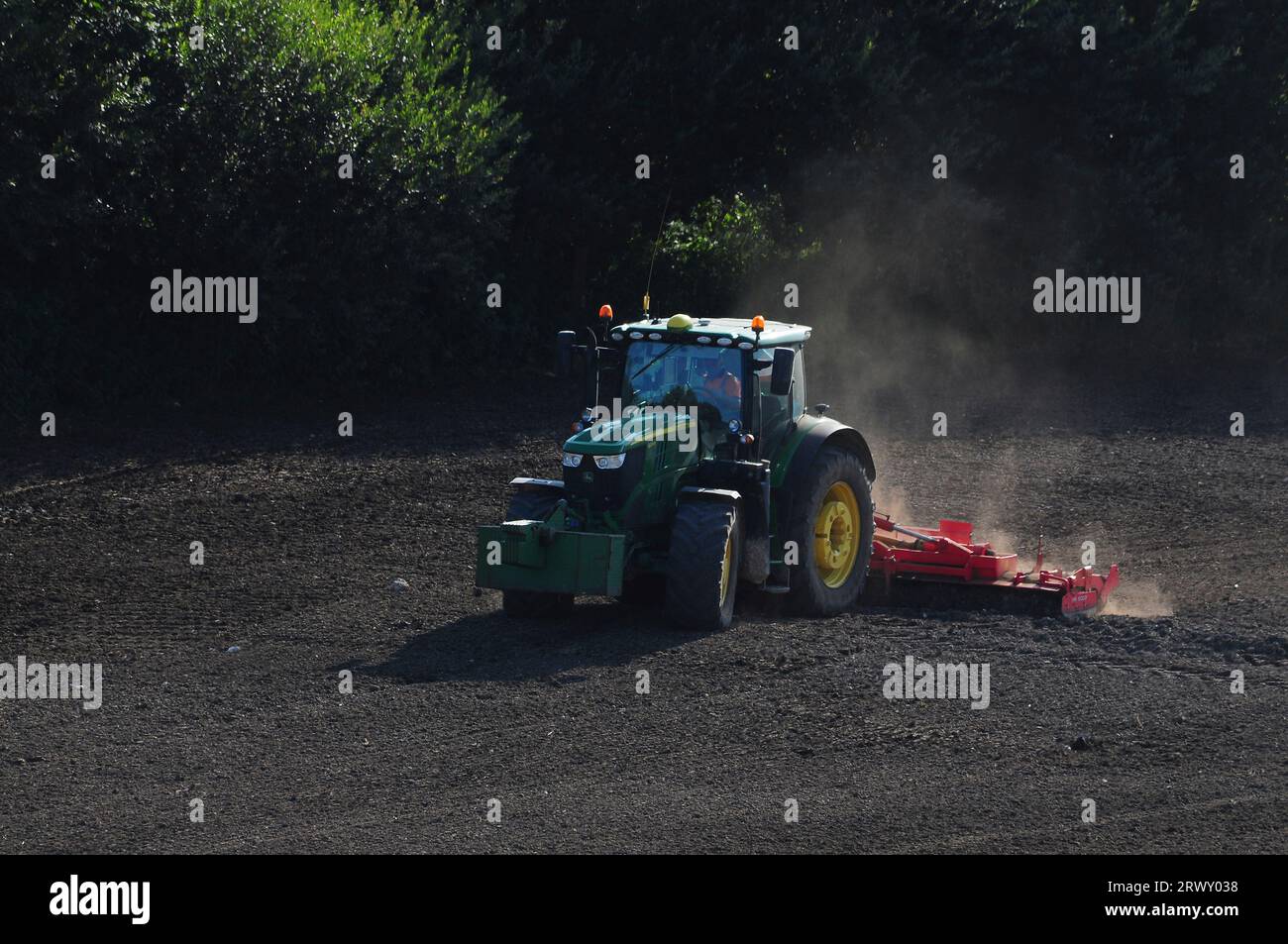 Tractor harrowing field in preparation for crop sowing in the Dorset ...