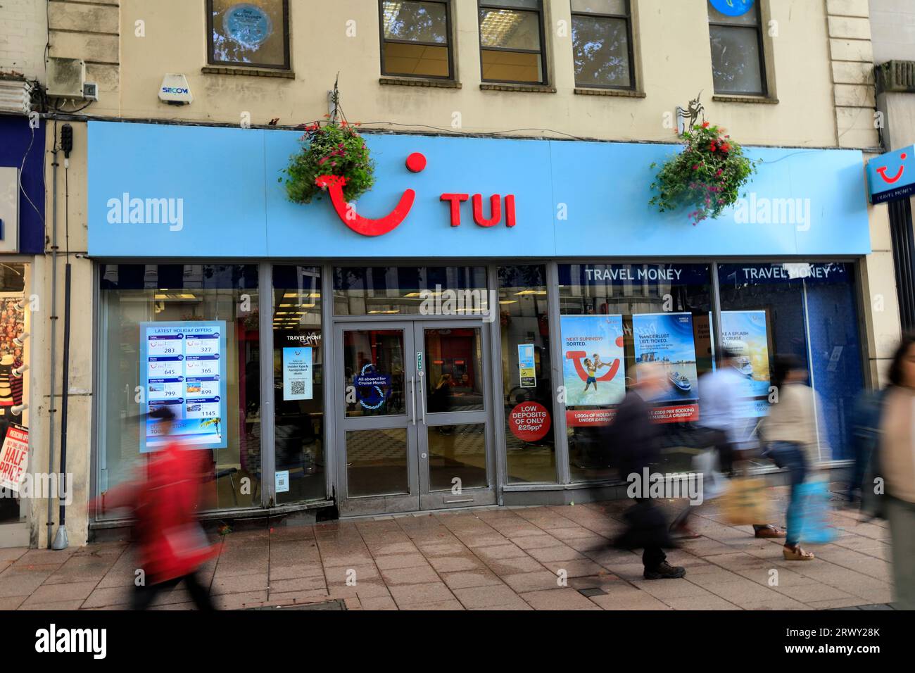 TUI travel agents store front with hanging flower baskets, with blurred ...