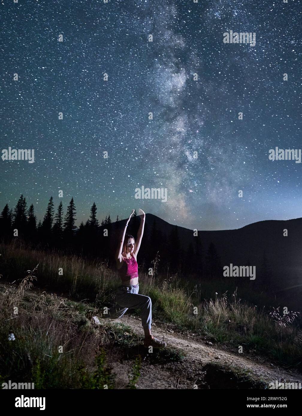 Sporty girl doing yoga pose in moutains on background of Milky Way ...