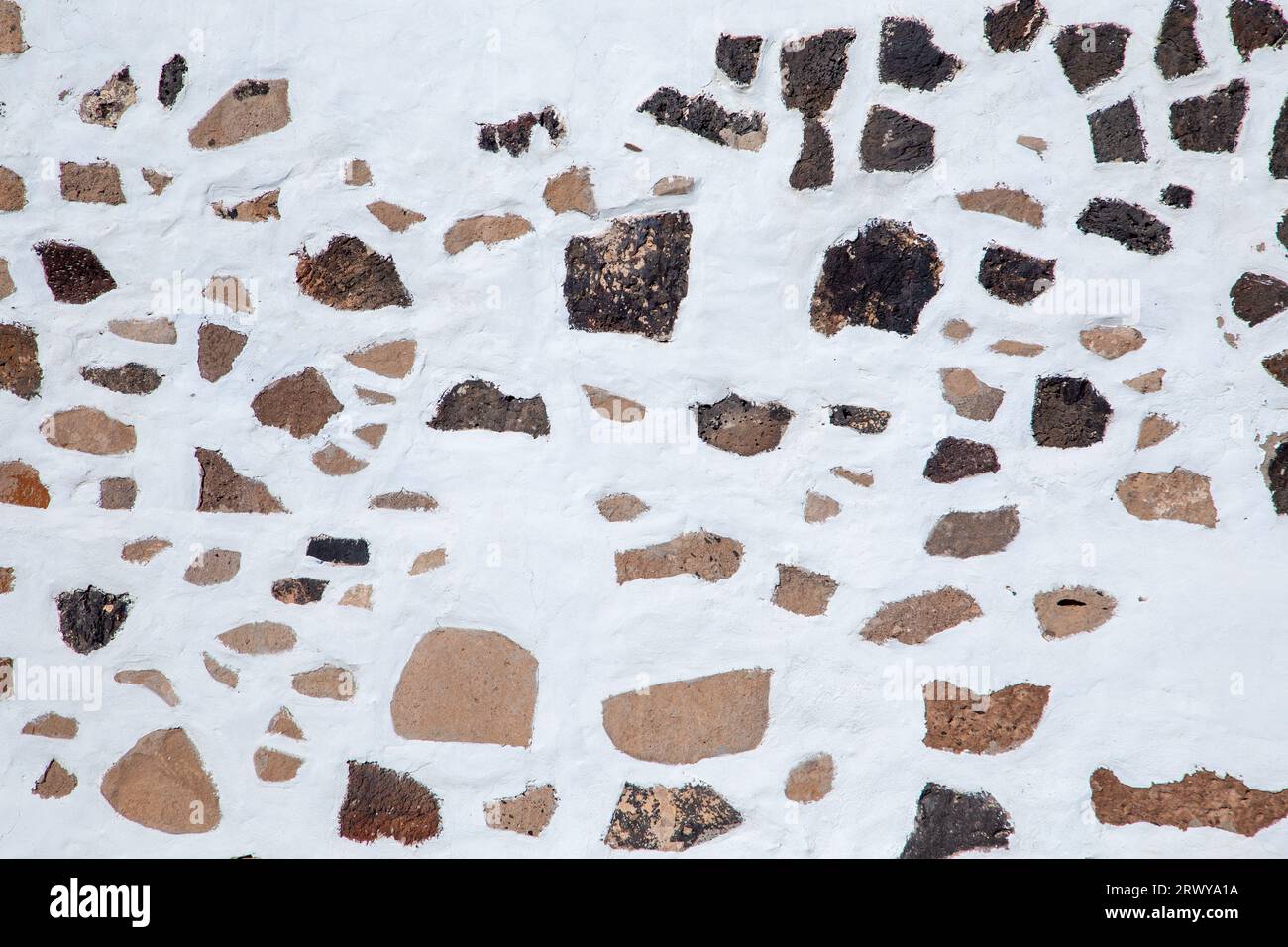 pattern of old stones integrated in a white painted plaster wall gives ...