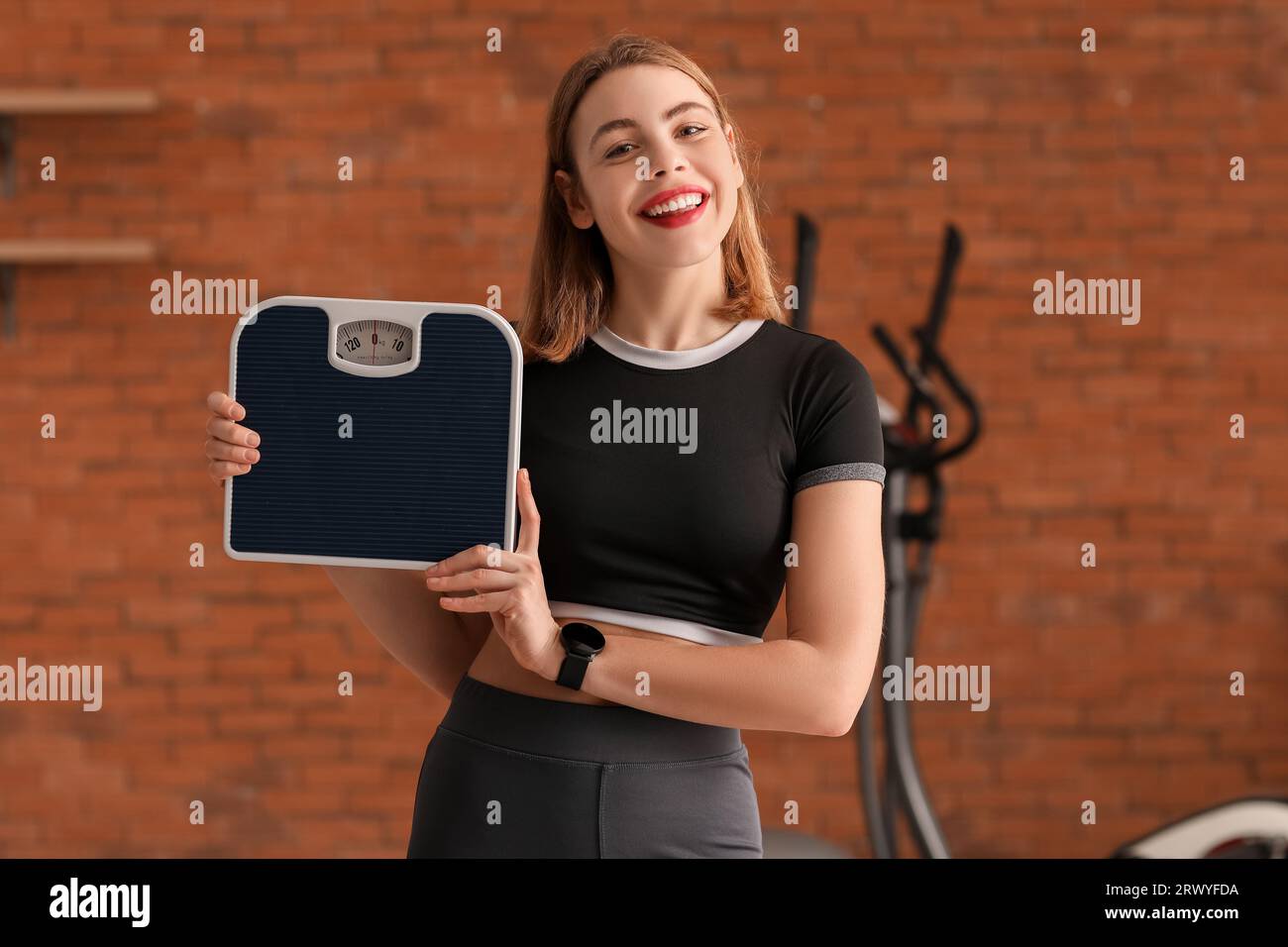Sporty young woman with scales in gym Stock Photo - Alamy