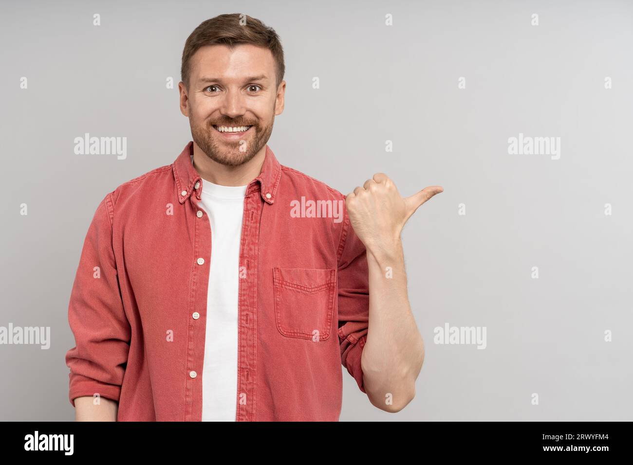 Man points with his thumb to side. Portrait of glad cheerful man ...
