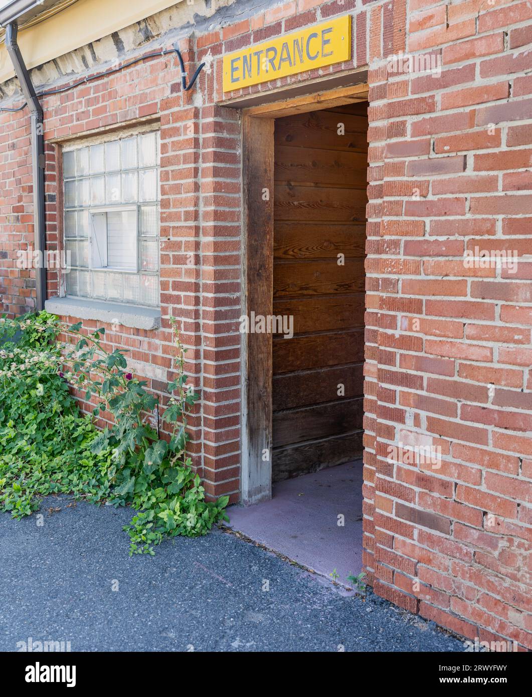ENTRANCE sign at open door of red brick commercial building shows a ...