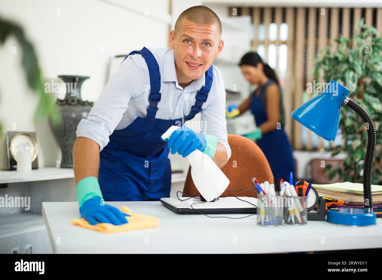 Man from cleaning service wiping office table Stock Photo - Alamy