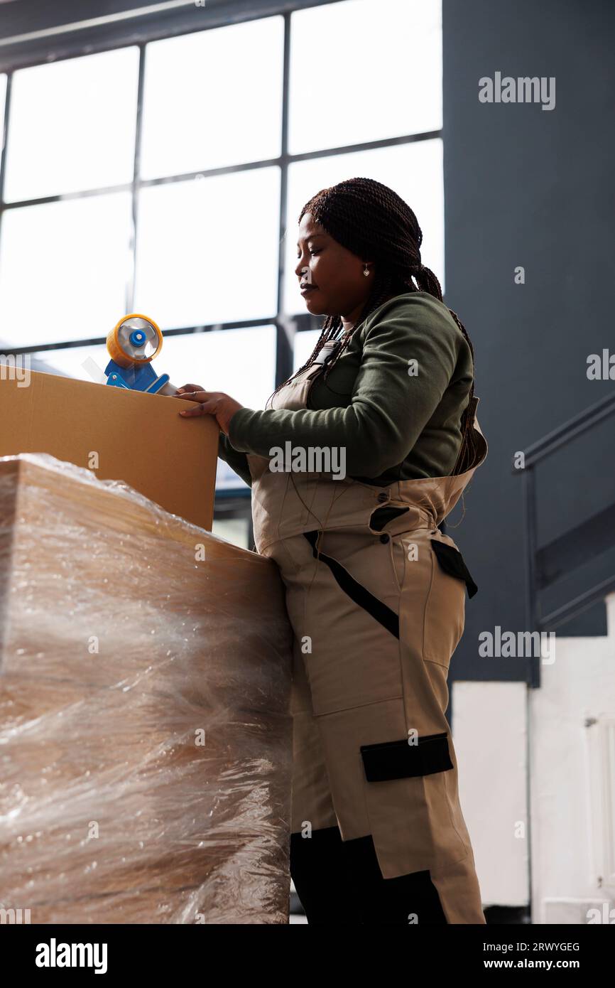 Small business employee putting adhesive tape on carton box, preparing ...