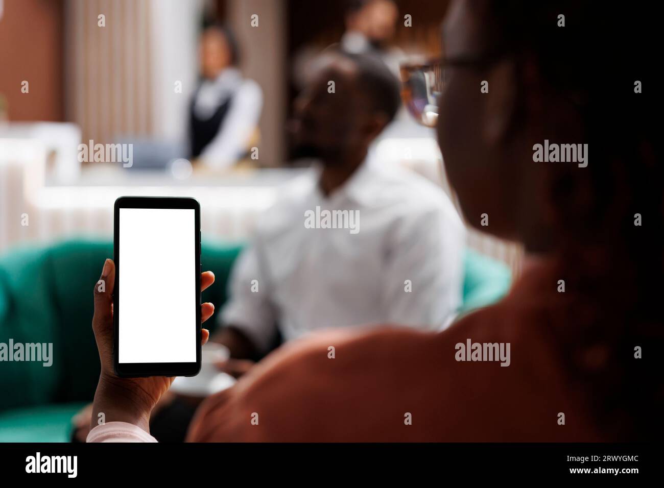 Tourist holding device with white screen, relaxing on sofa in lounge ...