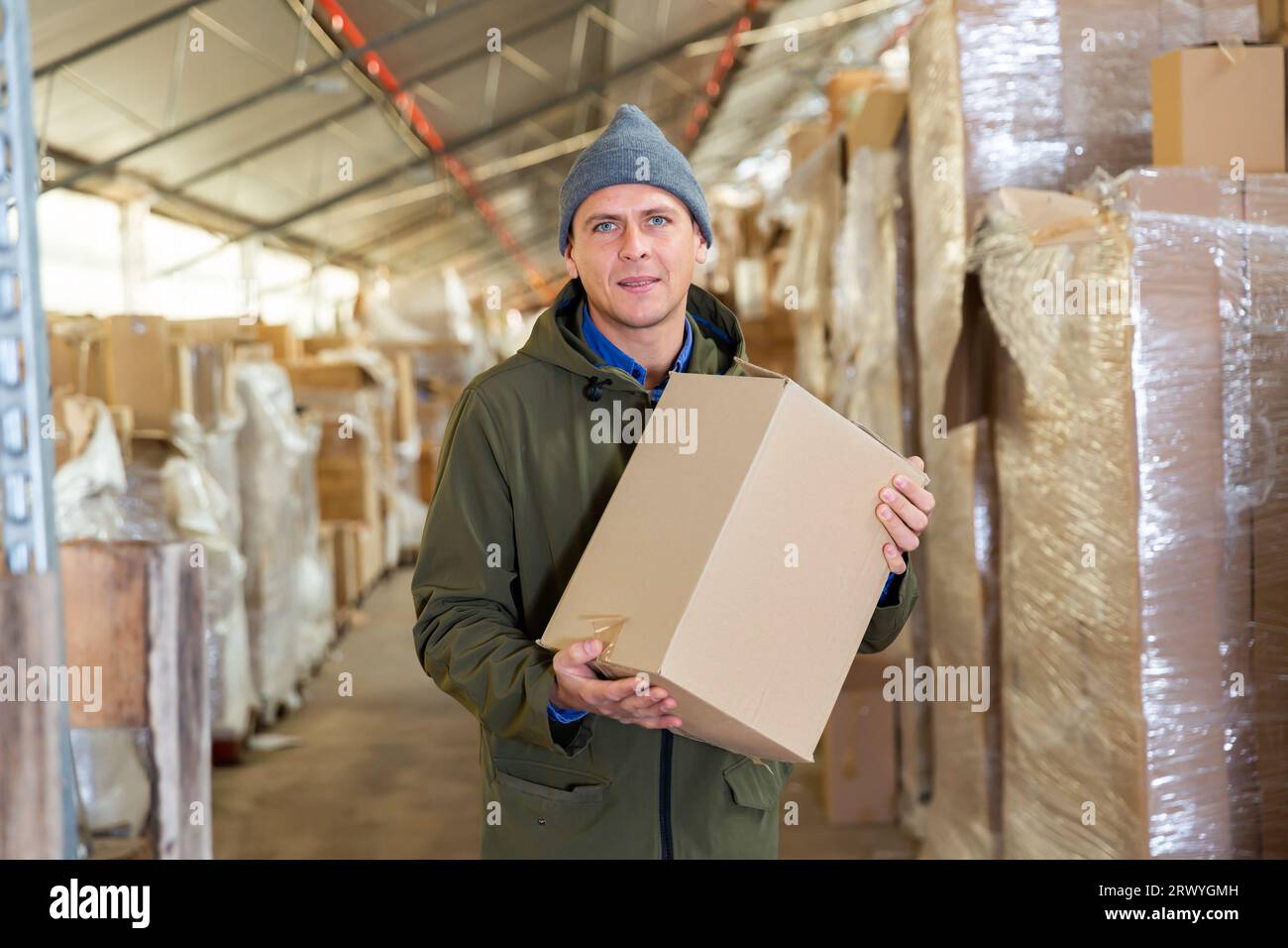 Loader stacks various boxes on racks in store Stock Photo - Alamy